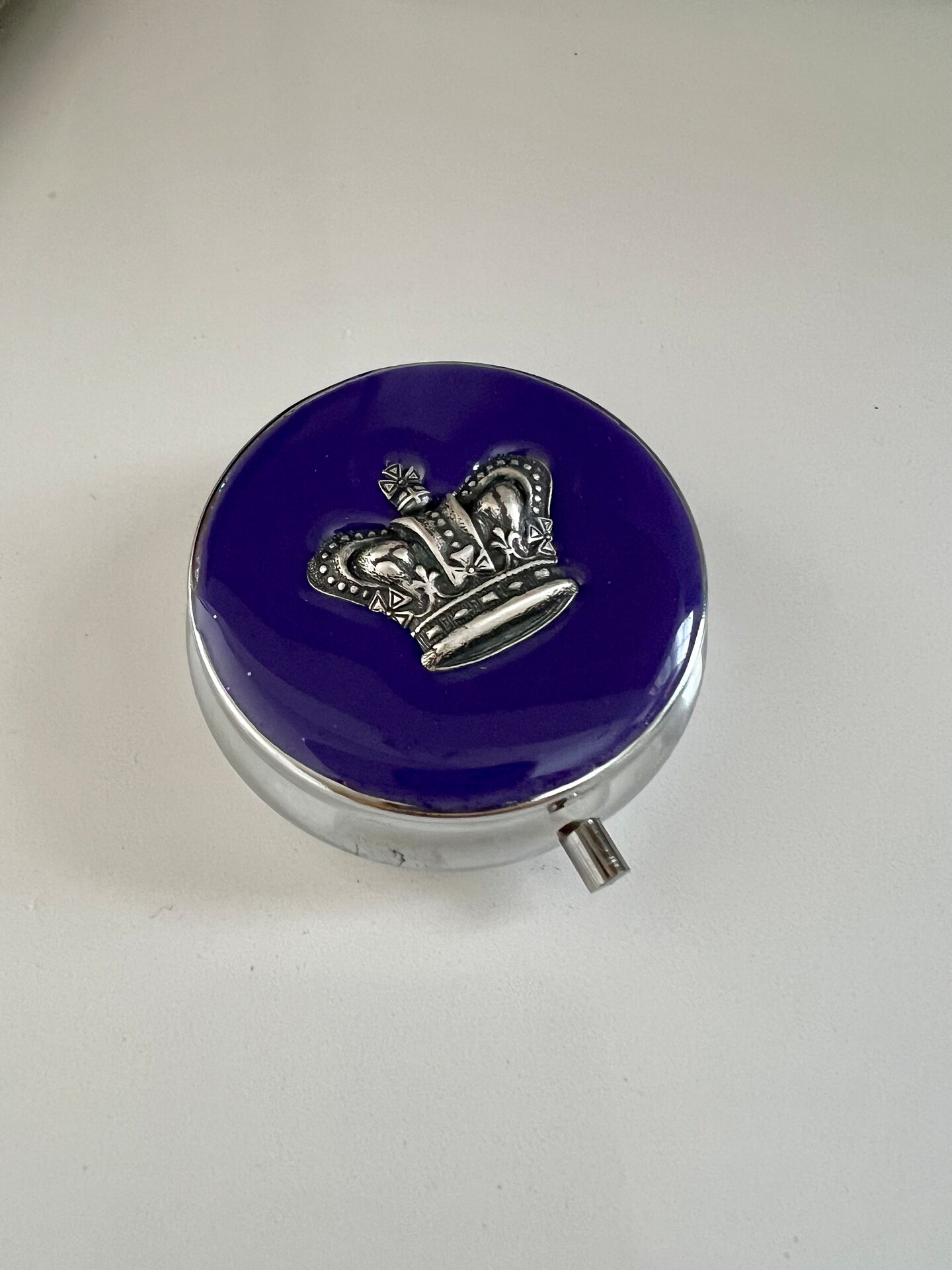 Pill box embellished with silver crown set on a royal purple resin ...