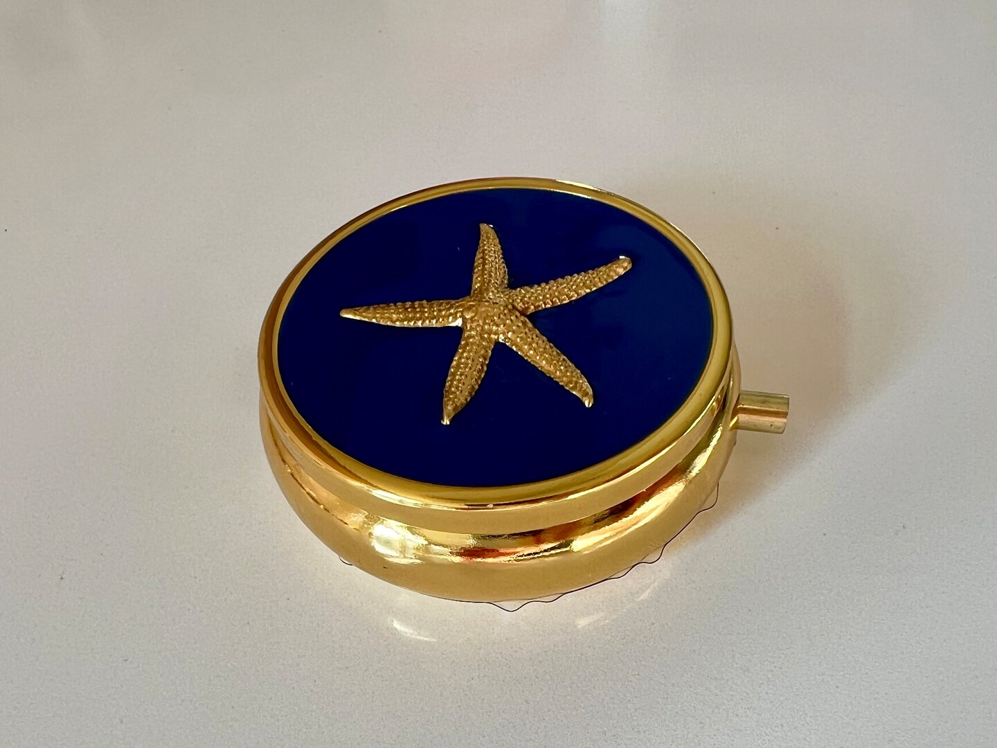 Pill box embellished with a gold starfish set on a French navy glossy ...